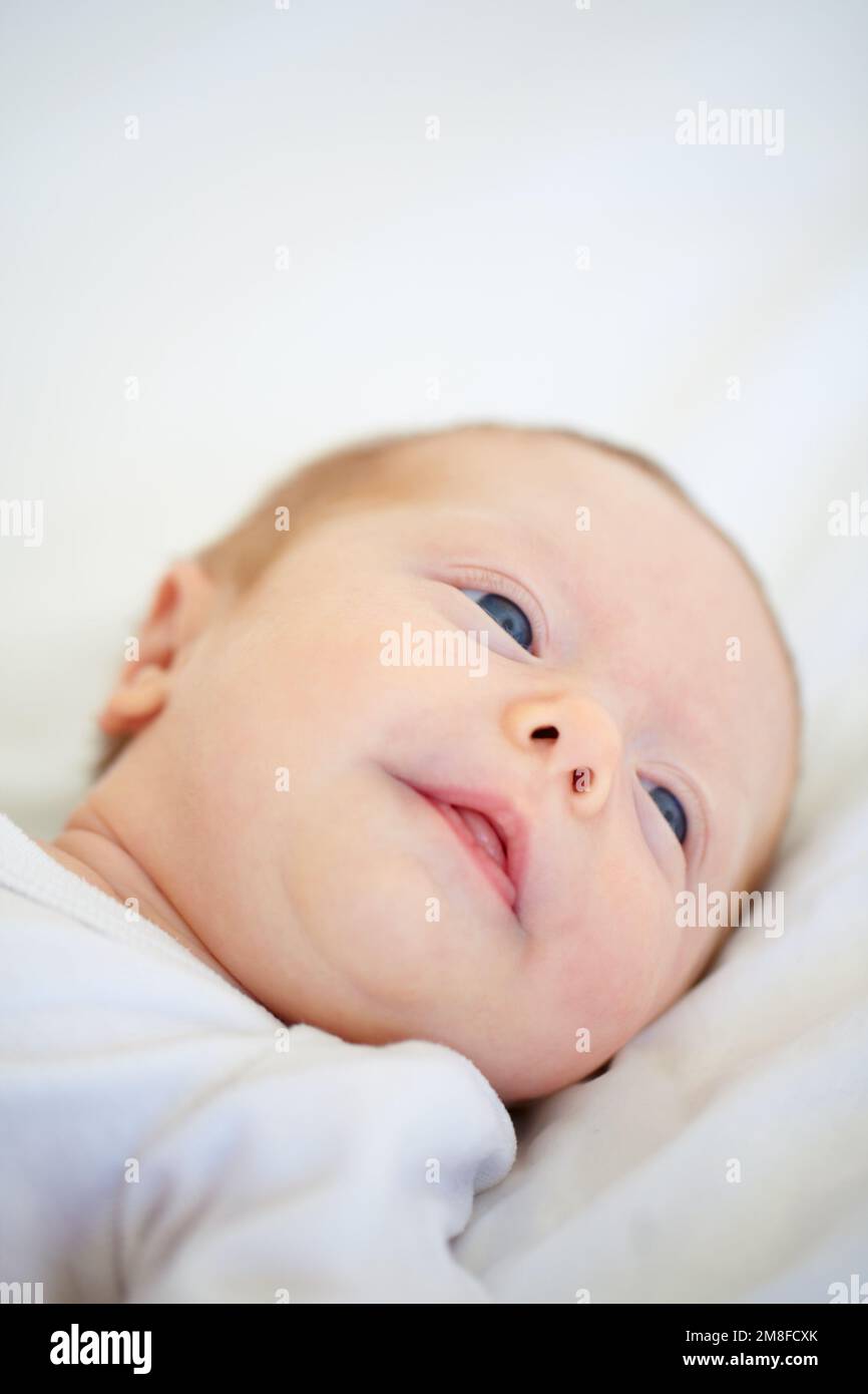 So many wonders...a happy-looking newborn baby lying in a cradle Stock ...