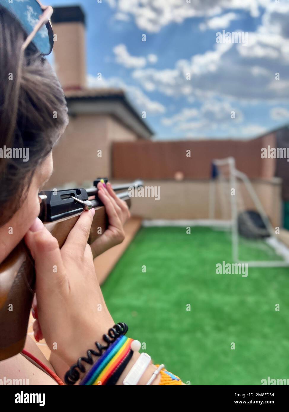 A vertical rear view of a woman aiming down the sights of a rifle Stock ...