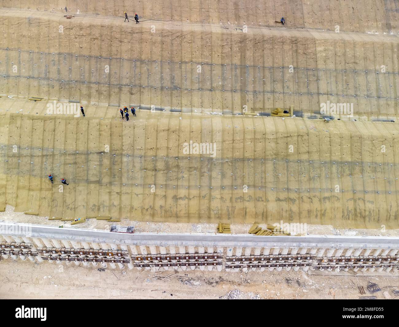 Mountain road constraction. Workers reinforce the slope over the new ...