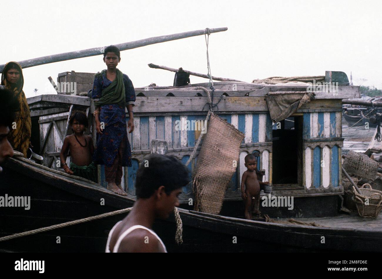 Refugees stand outside their shelter, a wrecked boat, in the aftermath ...