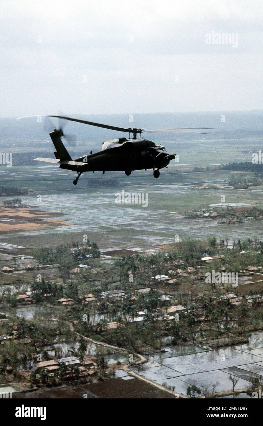 A UH-60 Black Hawk (Blackhawk) helicopter flies over a flooded area as ...