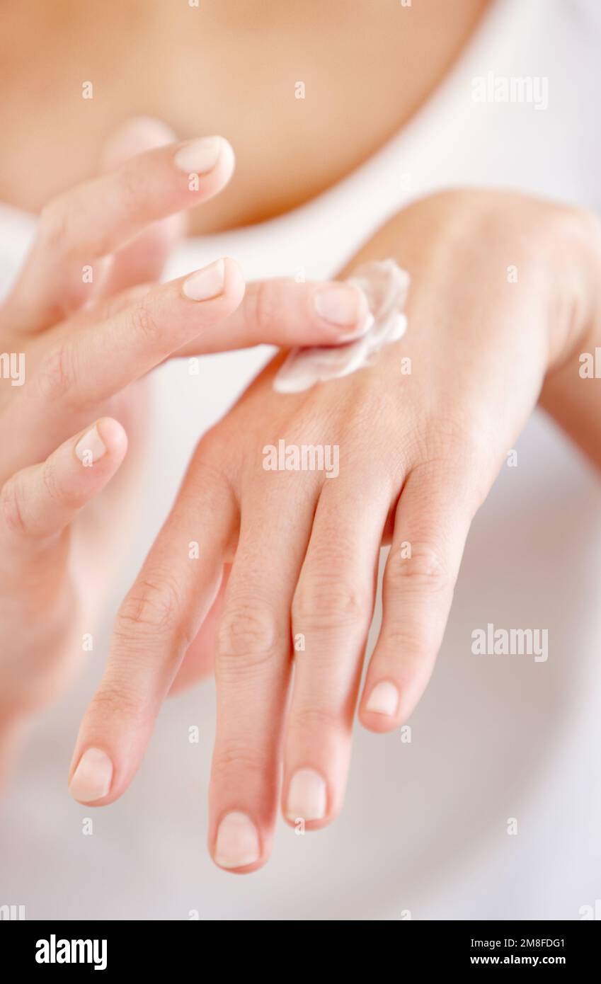 Moisturizing her skin. Cropped image of a young woman applying cream to ...