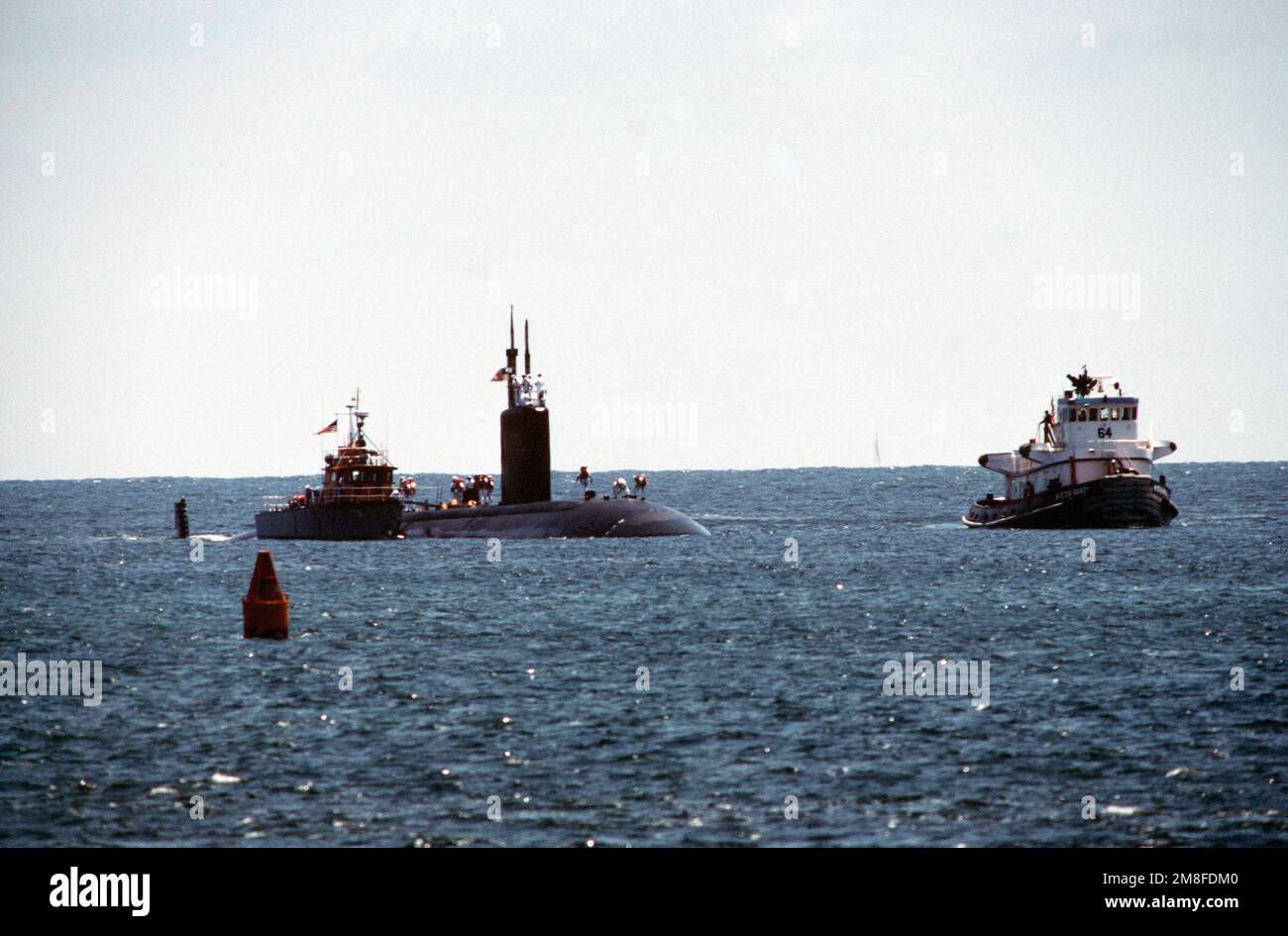 Accompanied by the torpedo retriever TR-5, left, and a commercial tug ...