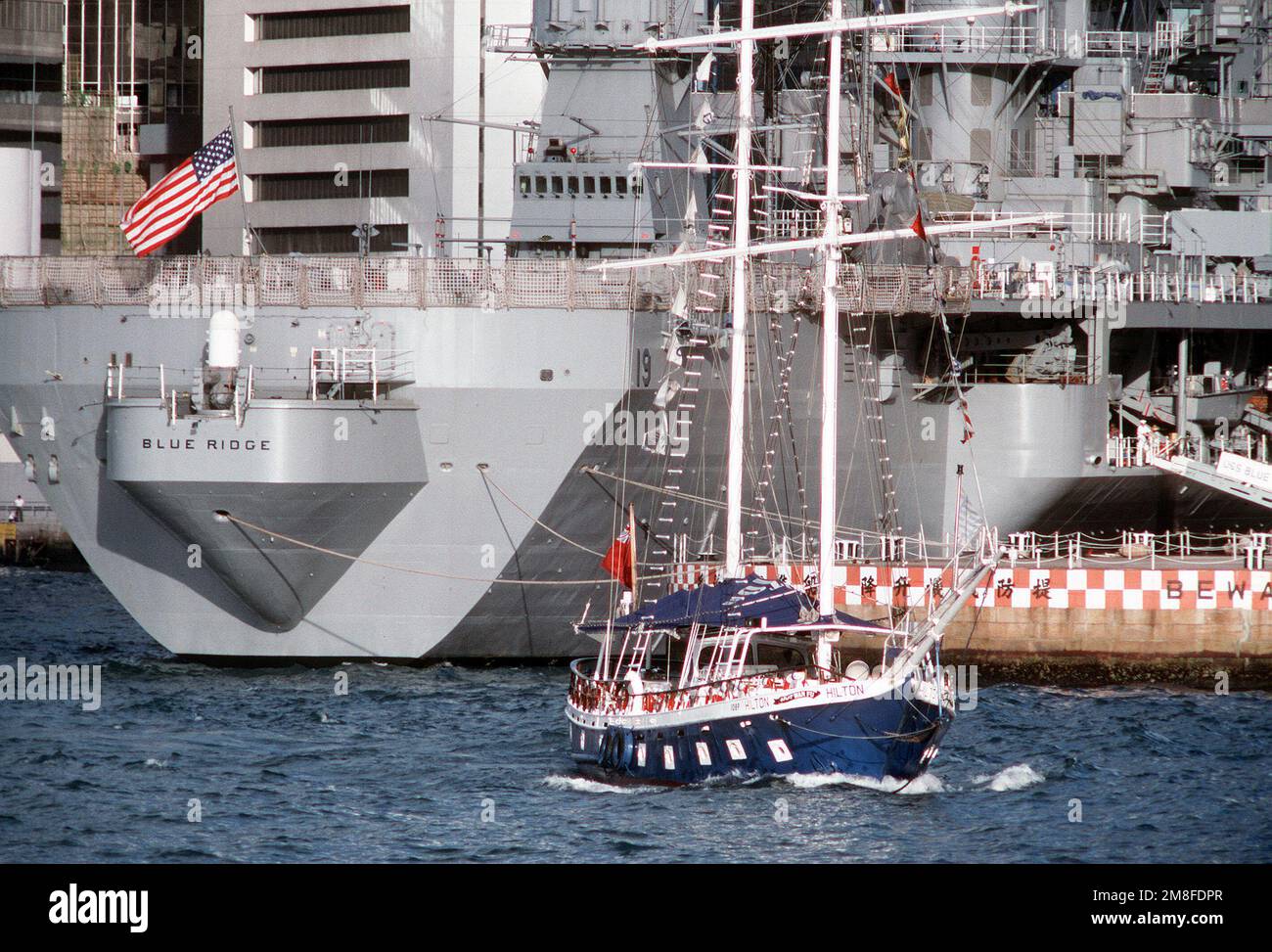A commercial boat passes the amphibious command ship USS BLUE RIDGE ...