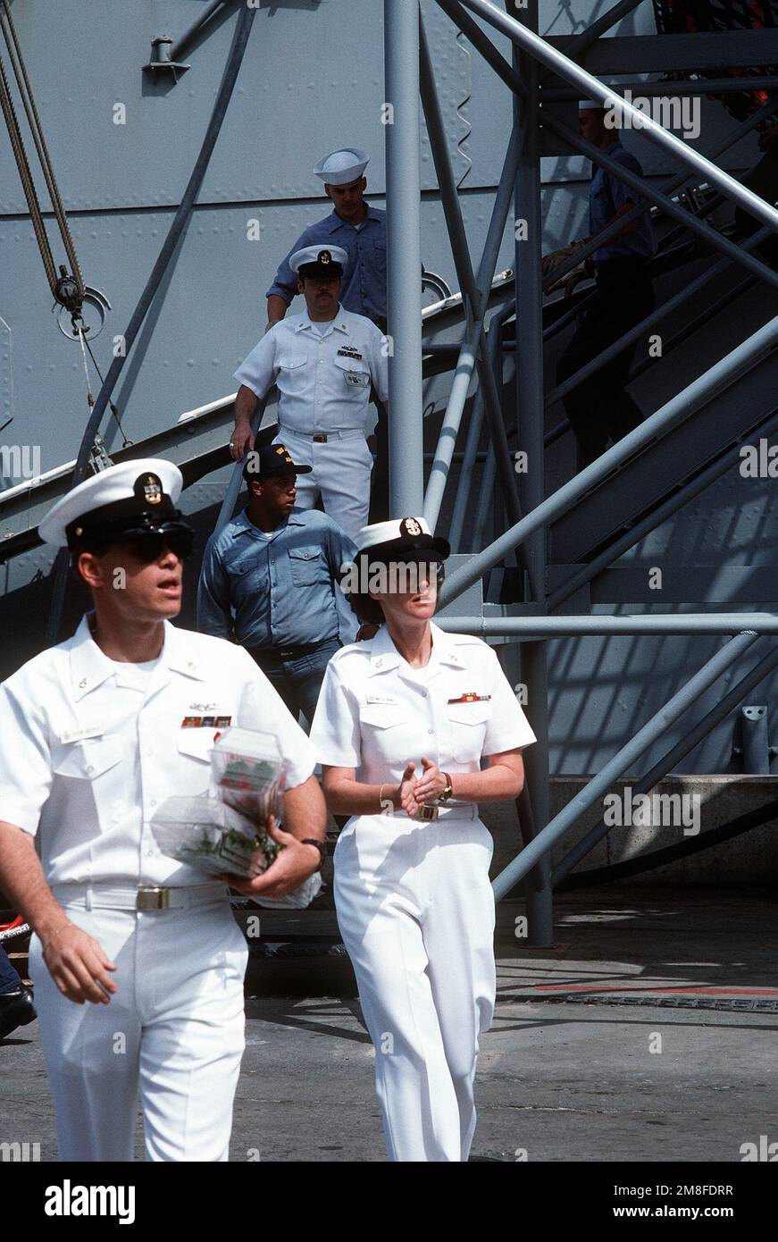 Two chief petty officers walk across the pier after disembarking from ...