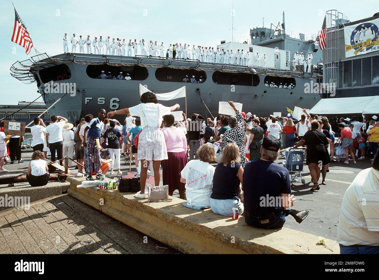Crew members stand at the railing aboard the combat stores ship USS SAN ...