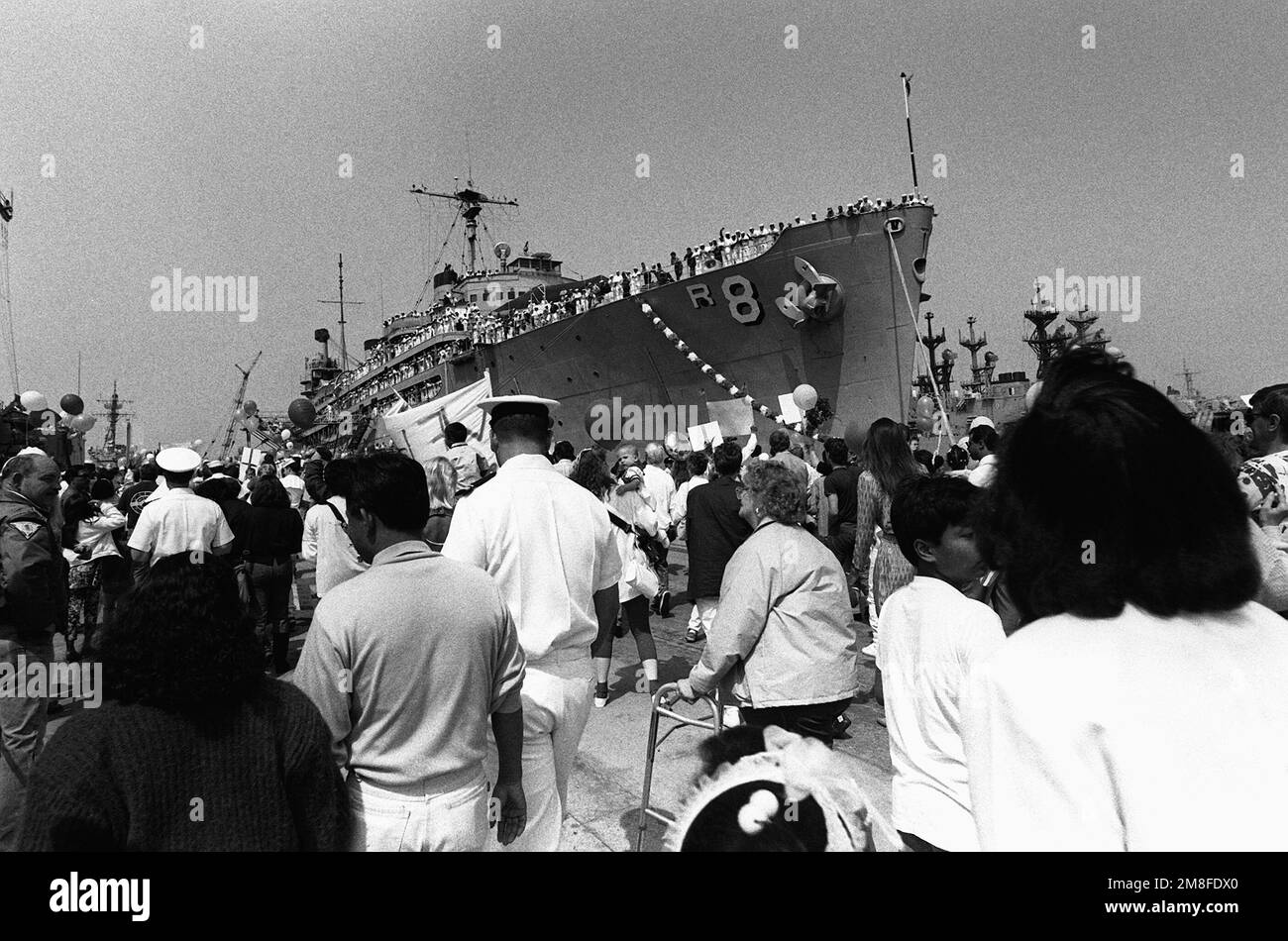 A crowd of family members and friends gather on the pier as they wait ...