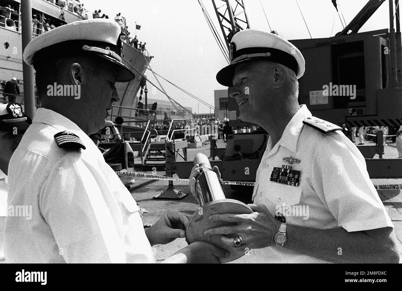 The captain of the repair ship USS JASON (AR-8) presents a momento to a ...