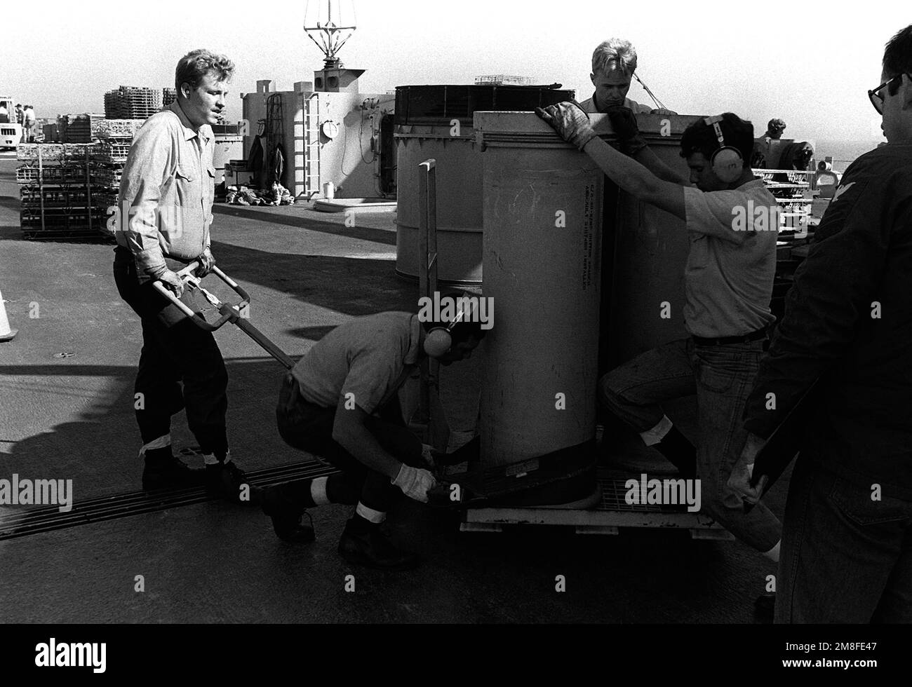 Crewmen position a Mark 4 propellant canister on a pallet on the deck ...