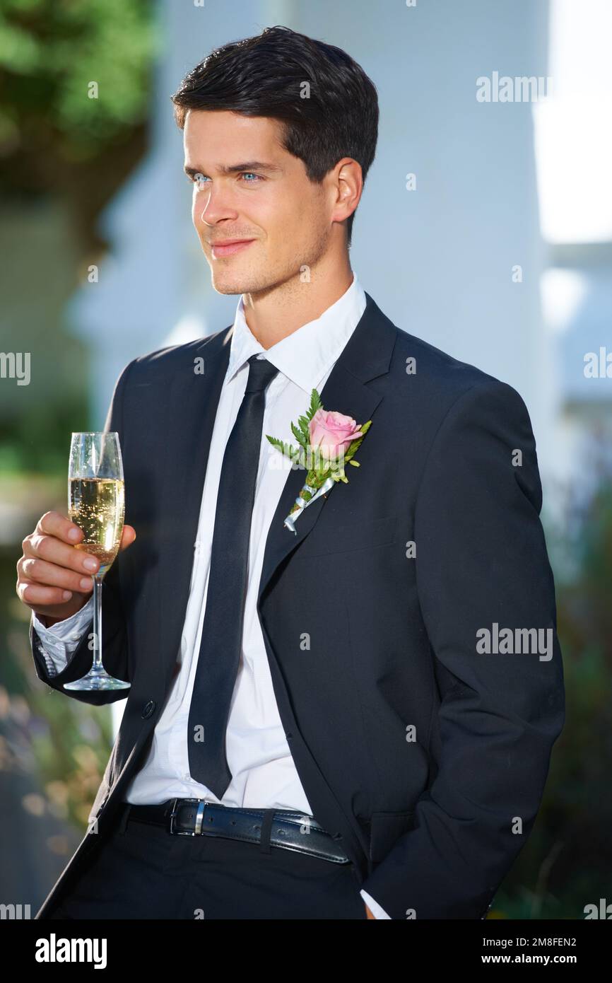 Taking in the reception. a young groom drinking a glass of champagne at ...