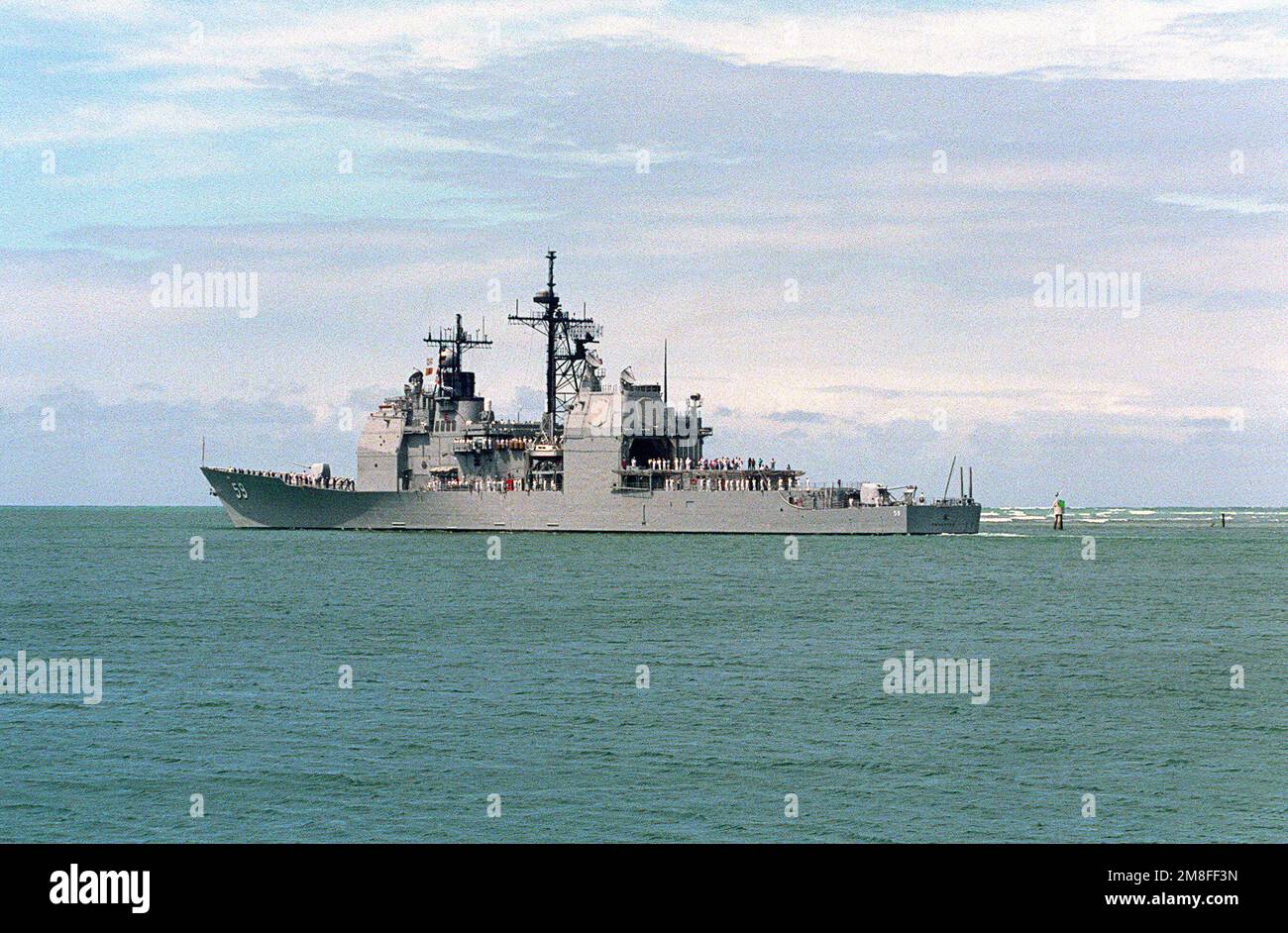 Crew members man the rails aboard the guided missile cruiser USS ...