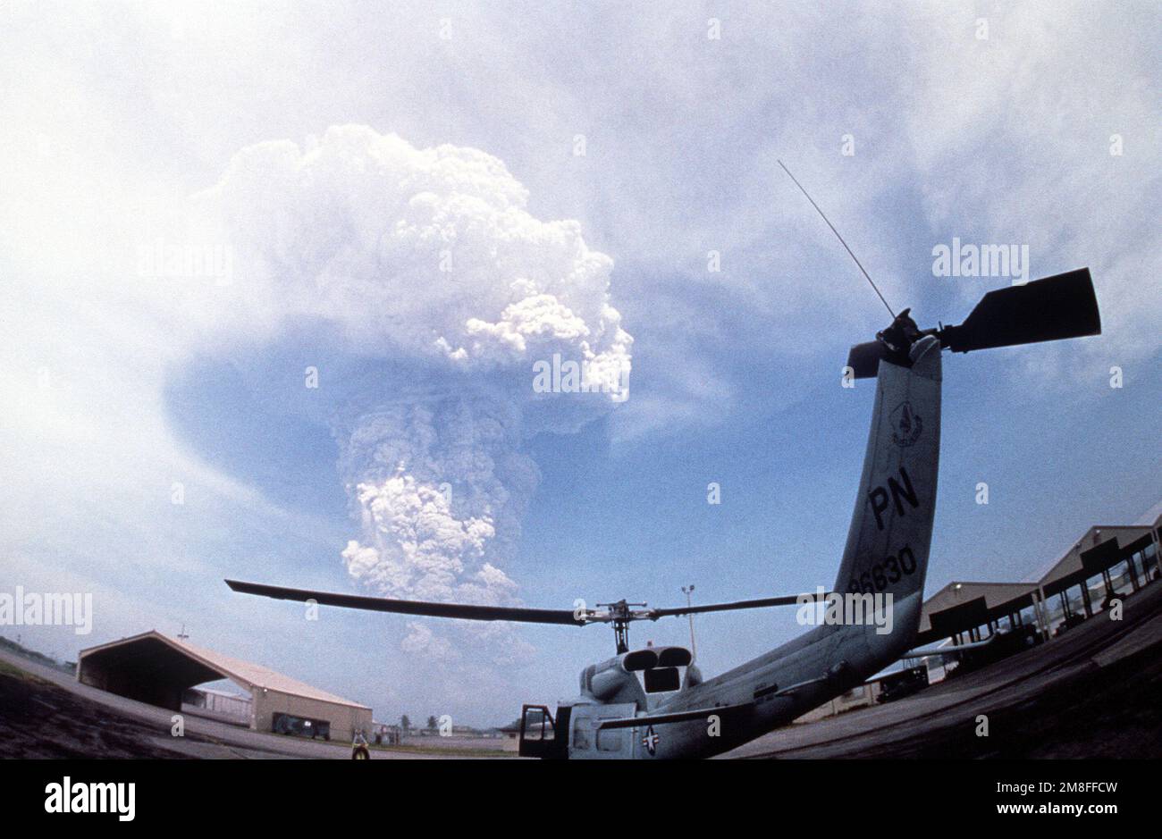 A mushroom cloud of ash from Mount Pinatubo billows in the background ...