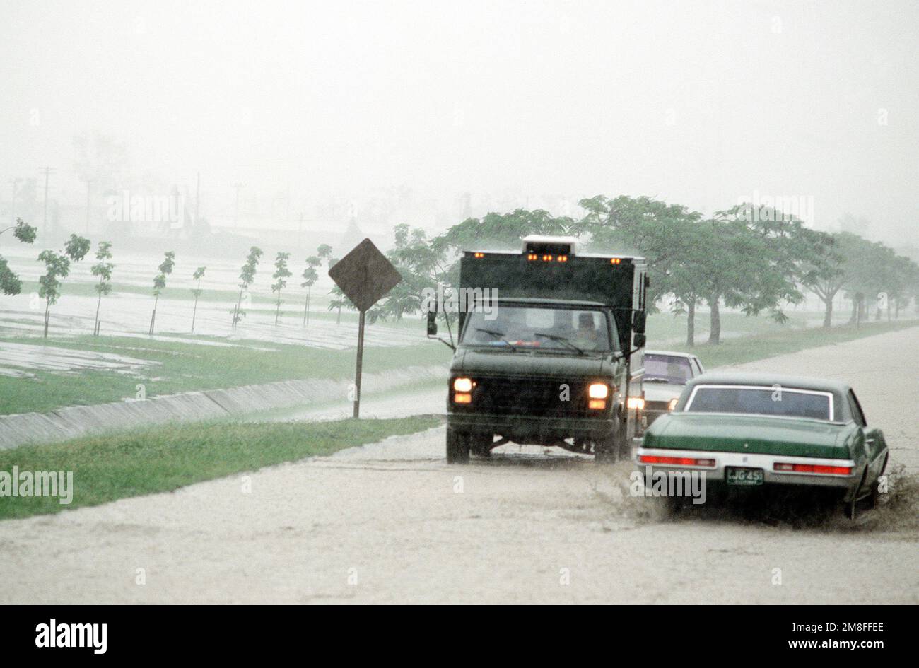 Vehicles drive along a flooded road as heavy rains inundate the base ...