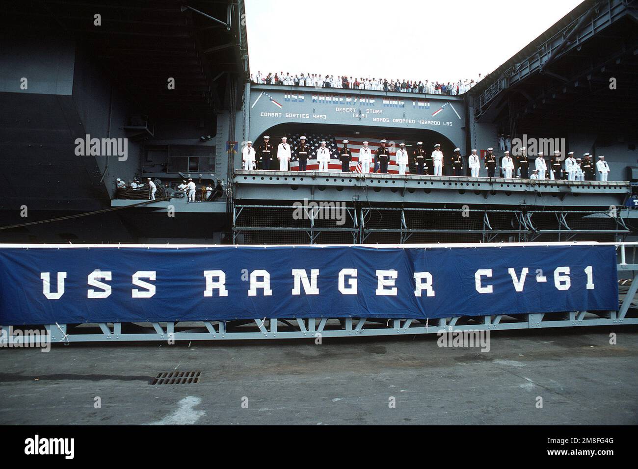 Sailors and members of the ship's Marine detachment stand at attention ...