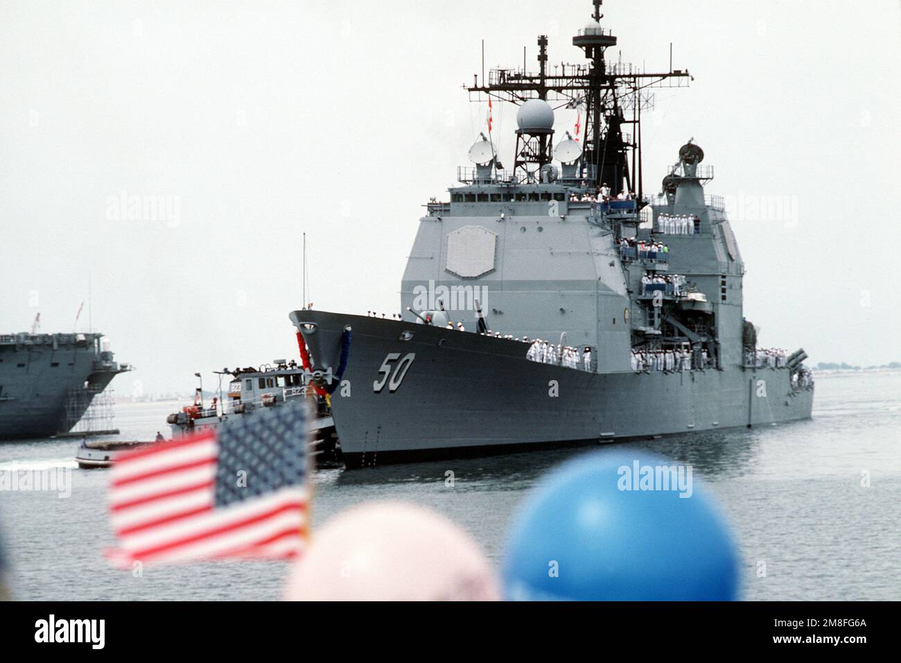 Sailors stand at the railing aboard the guided missile cruiser USS ...