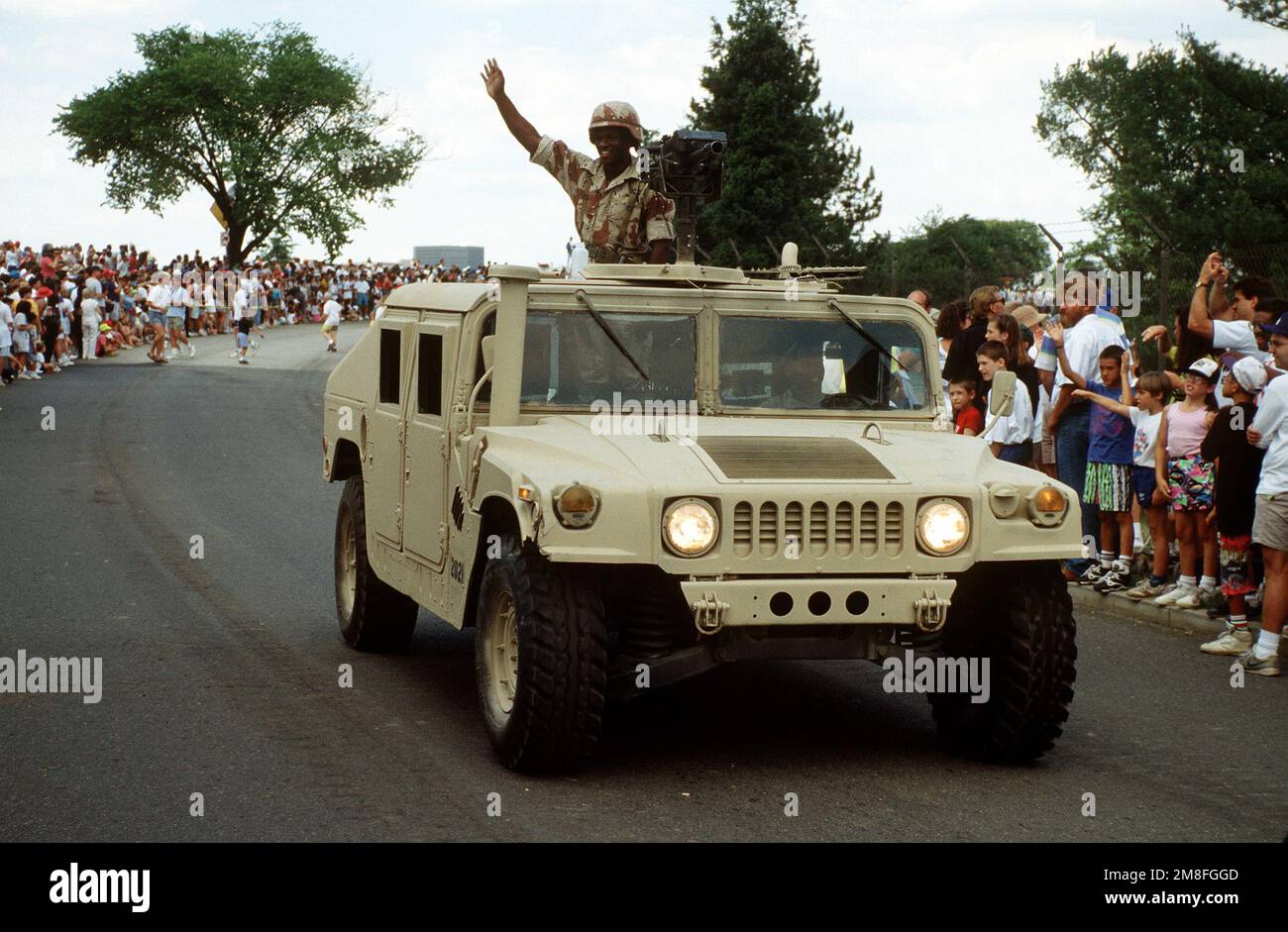 A Marine waves to the crowd as he stands behind the Mark 19 40mm ...