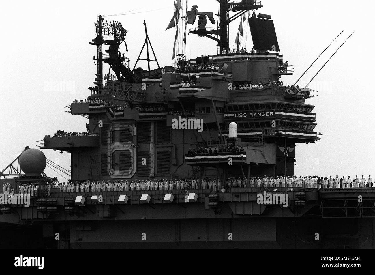 Sailors and Marines man the rails on and around the island structure of ...