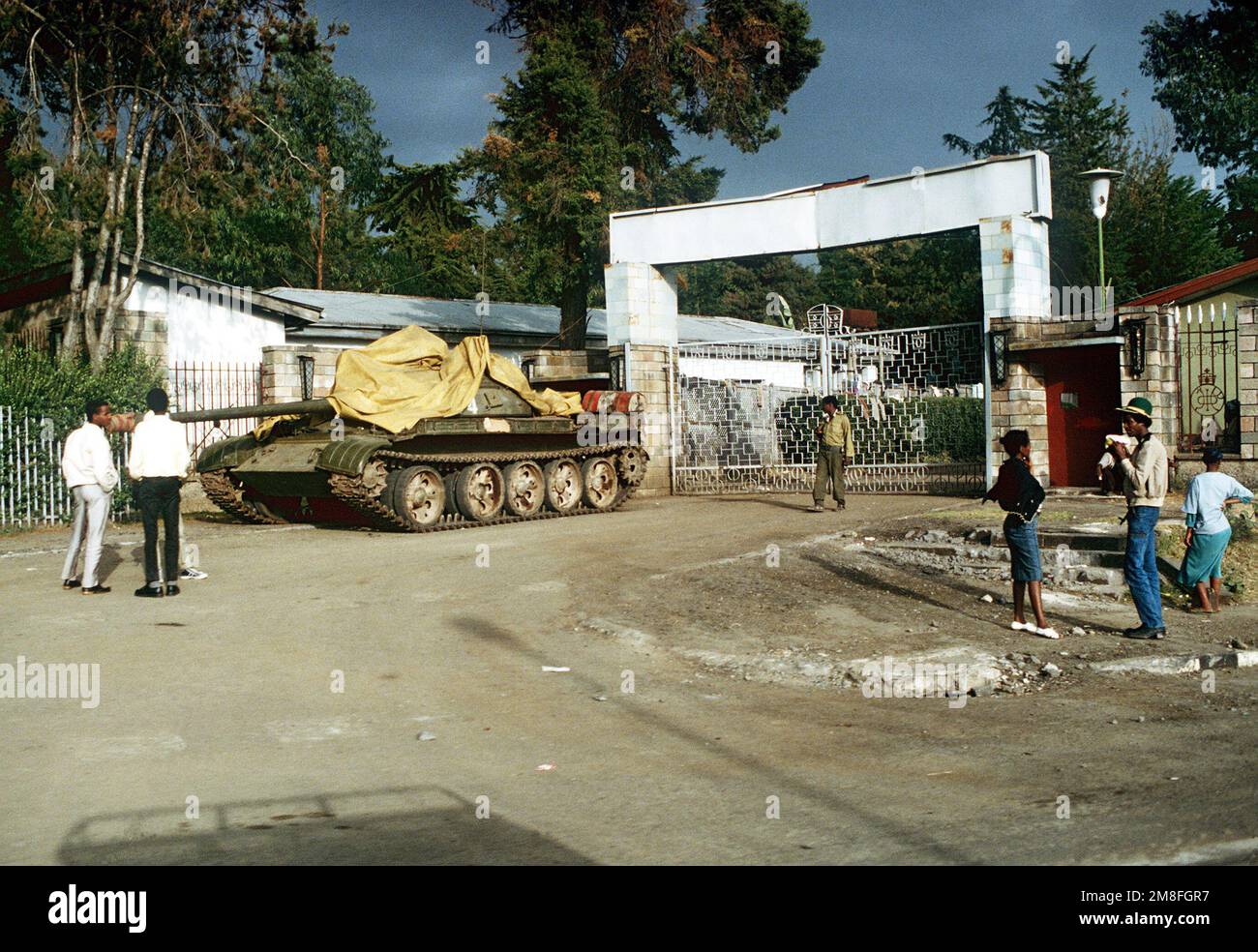 Local residents gather outside the Presidential Palace near a tank ...