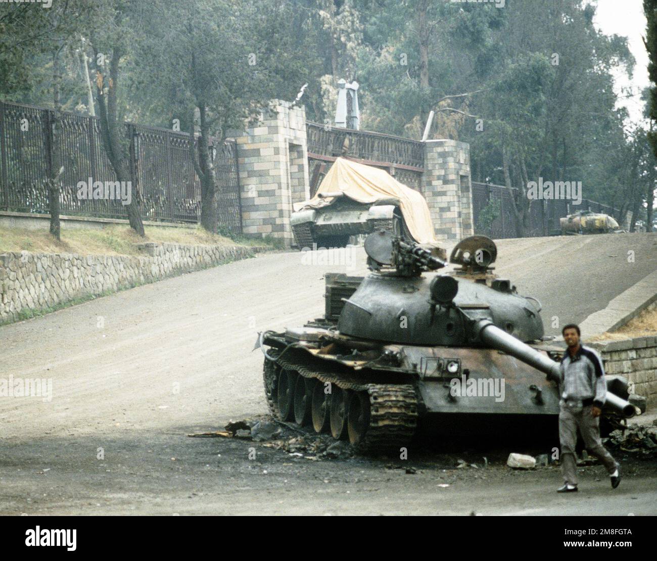 Local residents walk past a T-55 main battle tank stranded outside the ...