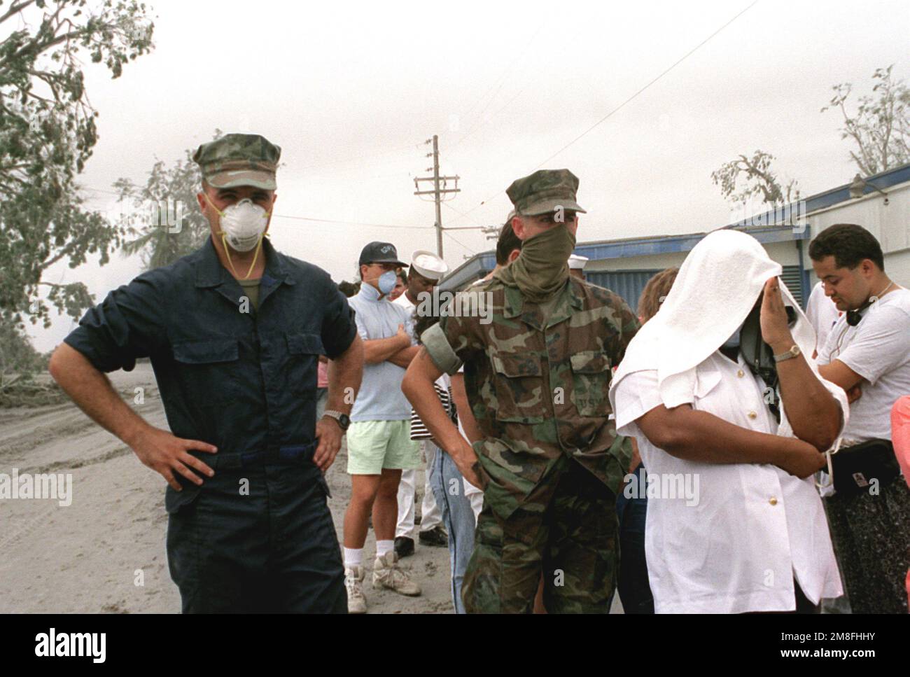 Military personnel wear masks as protection against inhaling ash during cleanup efforts in the ...