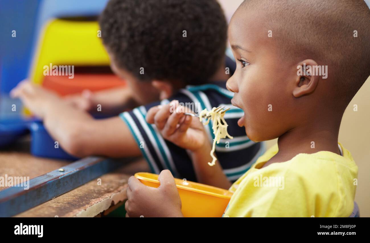Enjoying a nutritious snack. Preschool african american boy sitting in ...