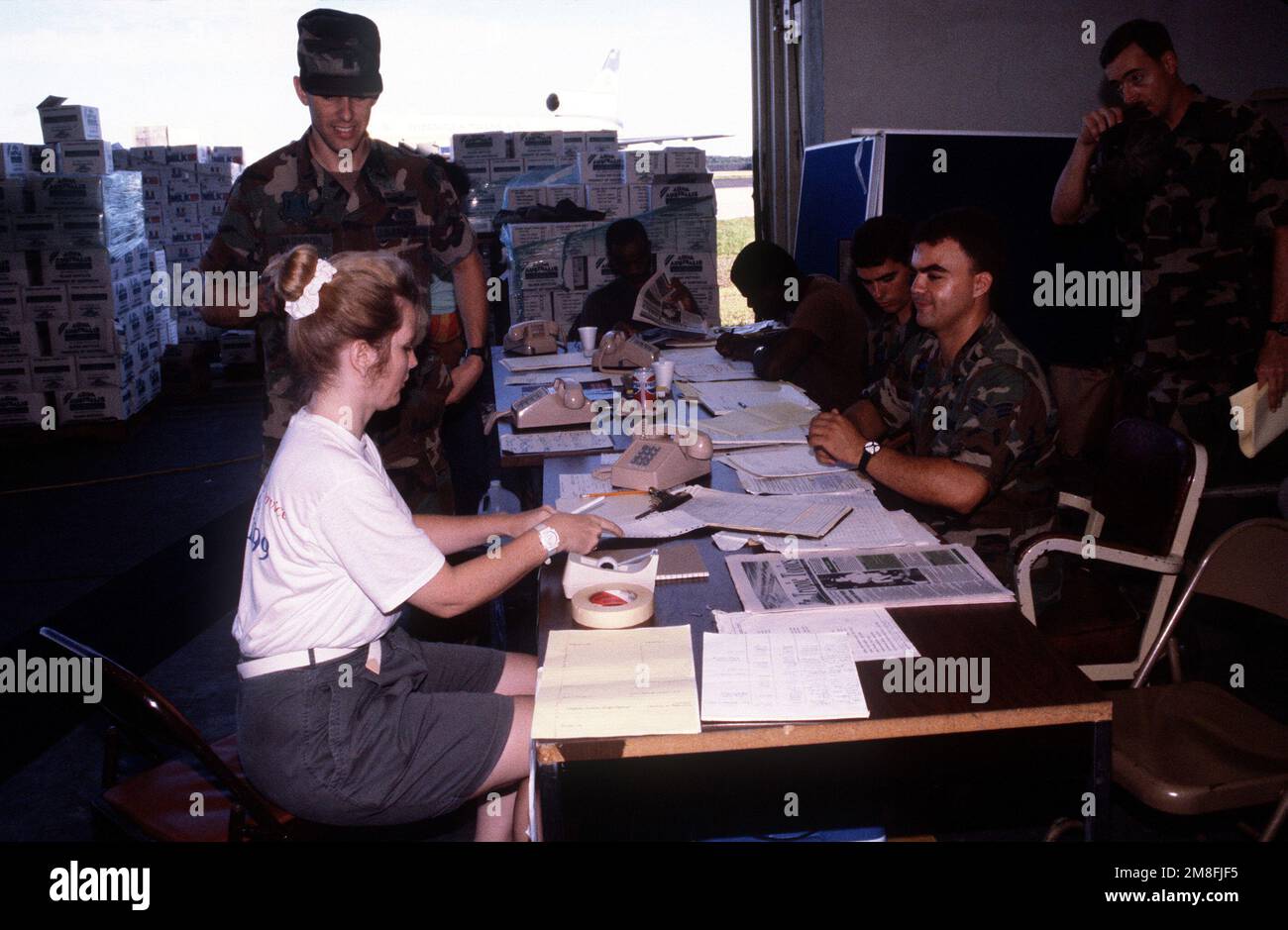 Air Force personnel assist a woman in filling out forms during ...