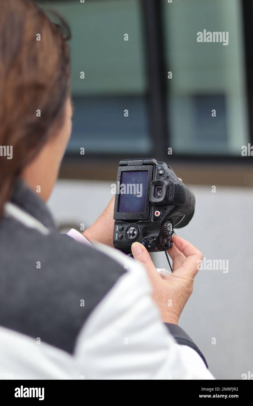 A vertical closeup of a woman taking pictures with a professional ...