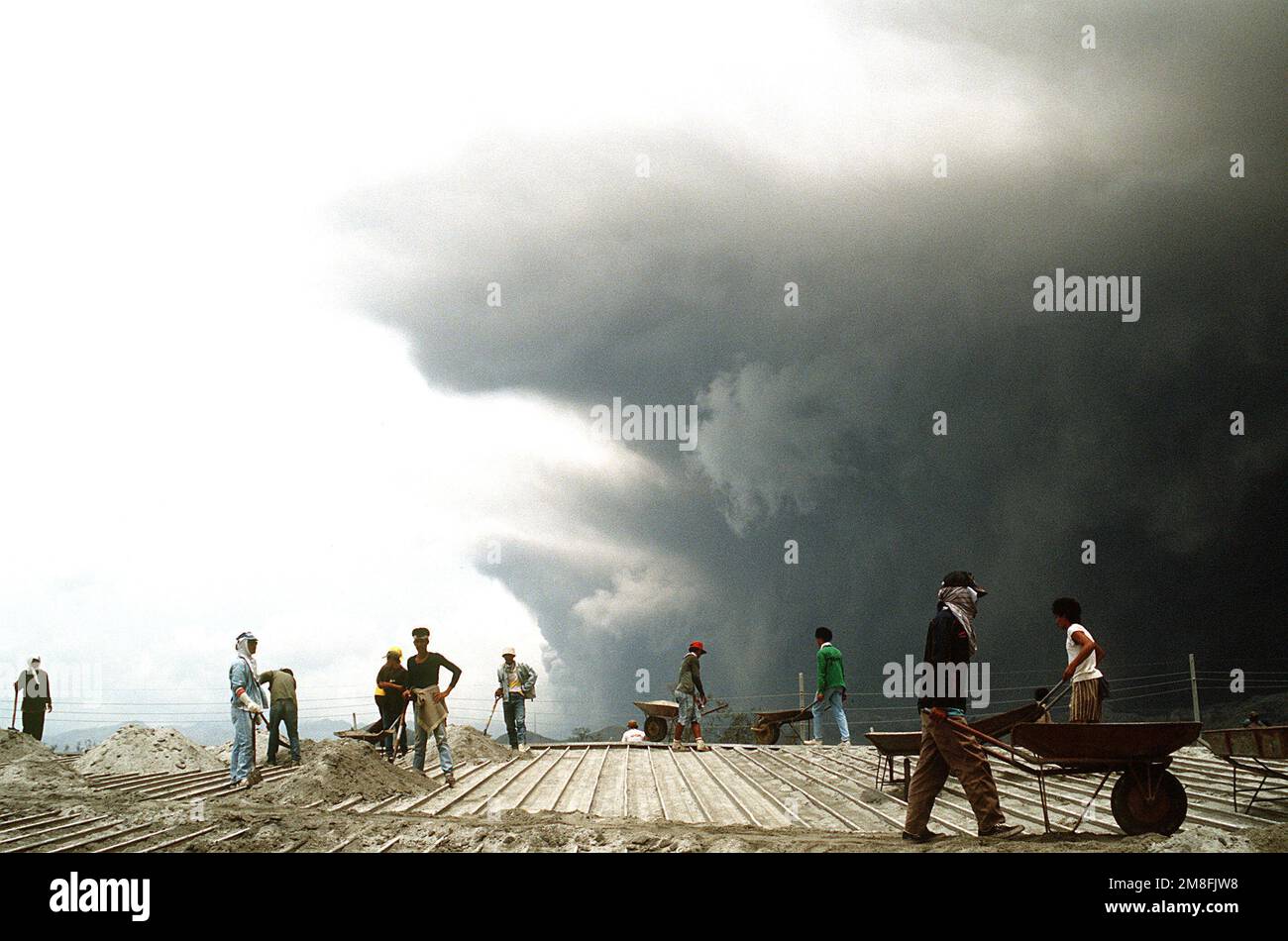 Filipino workers clear volcanic ash from the roof of a building as ash ...