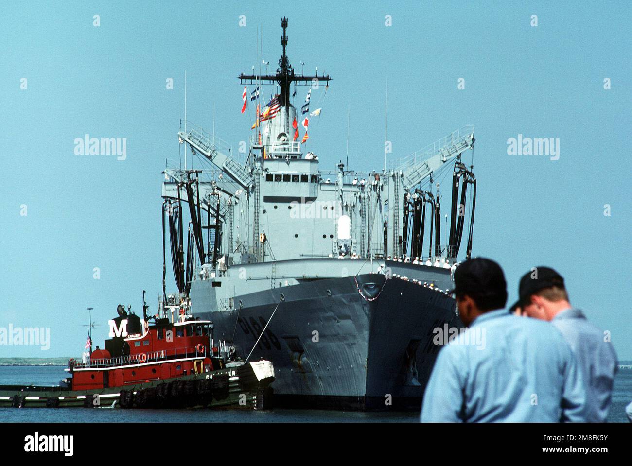 Line handlers stand by on the pier as a commercial tug boat guides the ...
