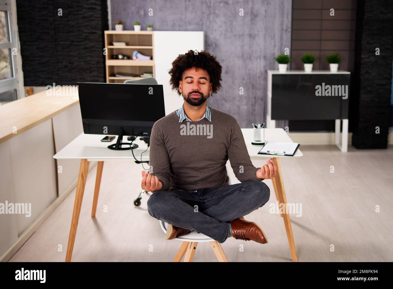 African American Male Meditation In Office Near Computer Stock Photo ...