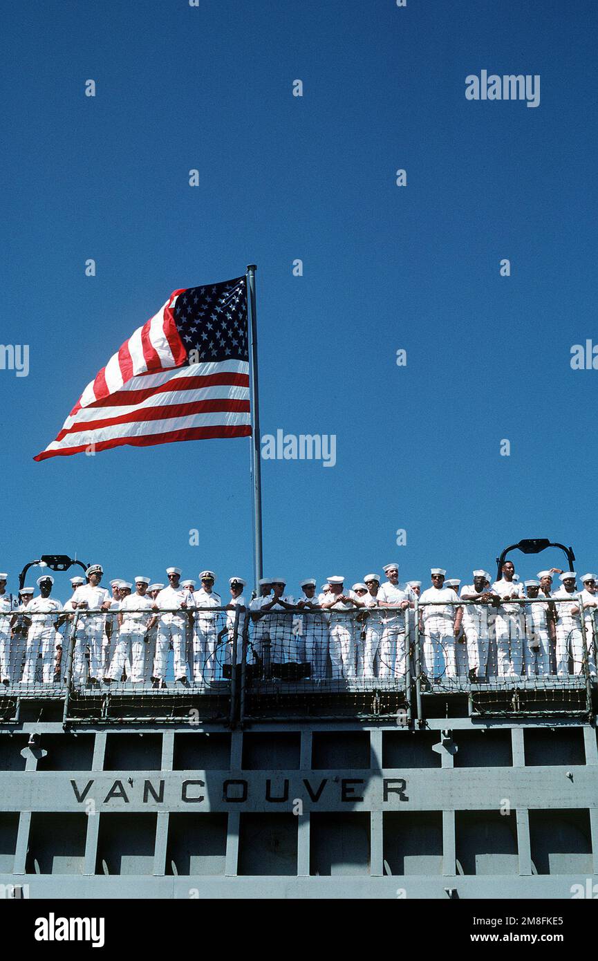 Officers and enlisted men stand beneath the colors at the stern of the ...