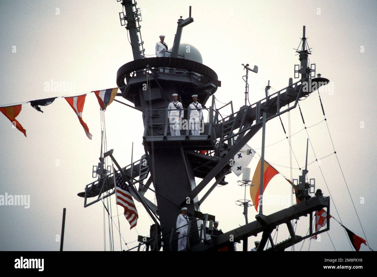 Sailors stand on the mast of the guided missile destroyer USS ARLEIGH ...