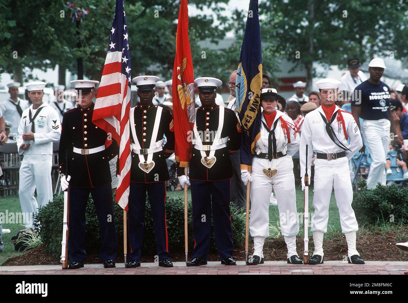 Members of a joint Navy-Marine Corps color guard stand at parade rest ...