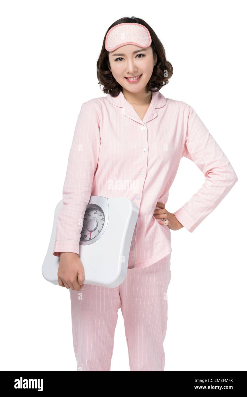 Young woman in a night-dress and holding a scale Stock Photo - Alamy