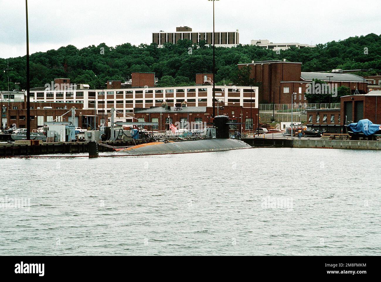 A Permit class nuclear-powered attack submarine is tied up in pier area ...