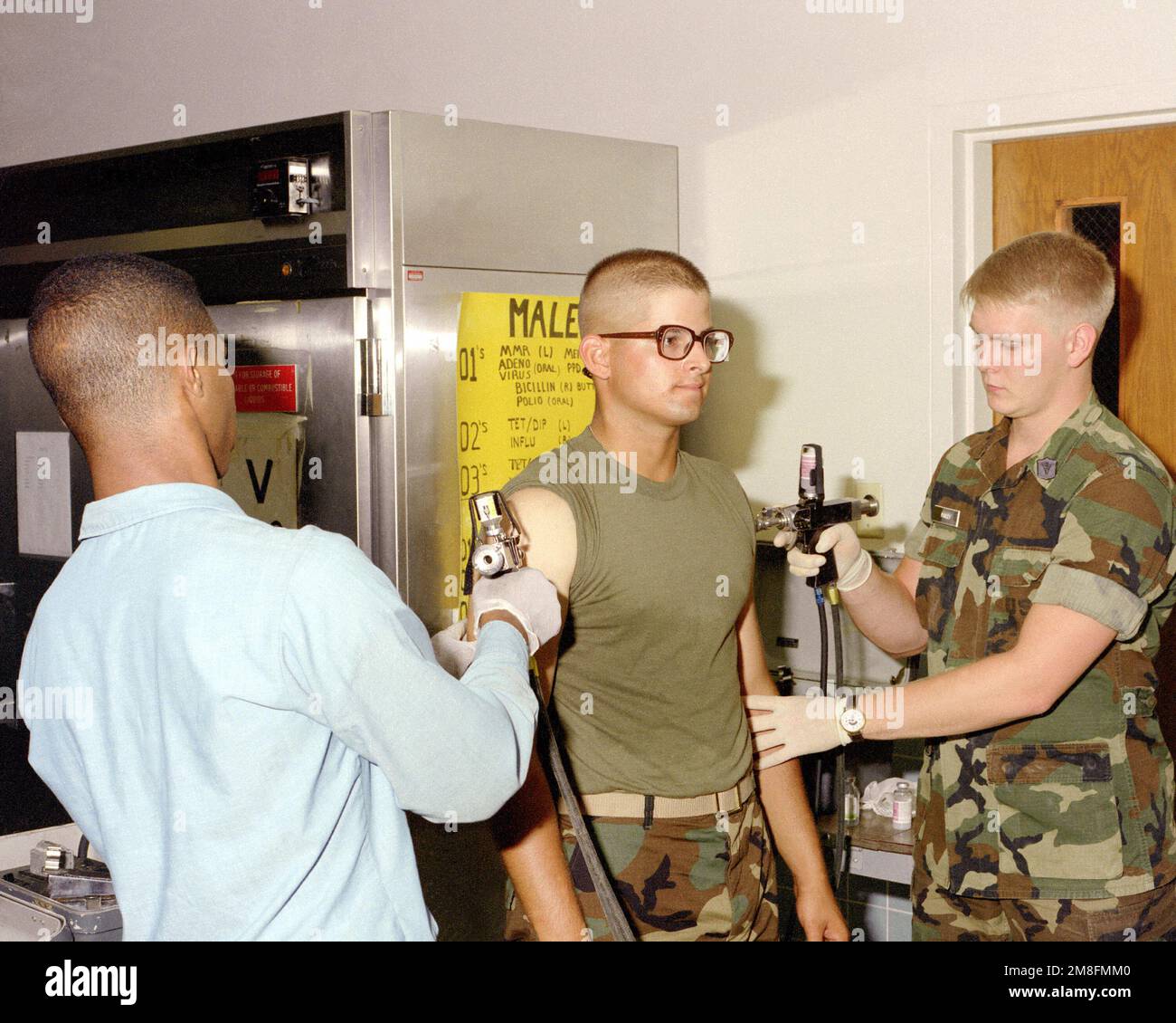 Navy hospital corpsemen give a recruit immunization injections. Base ...