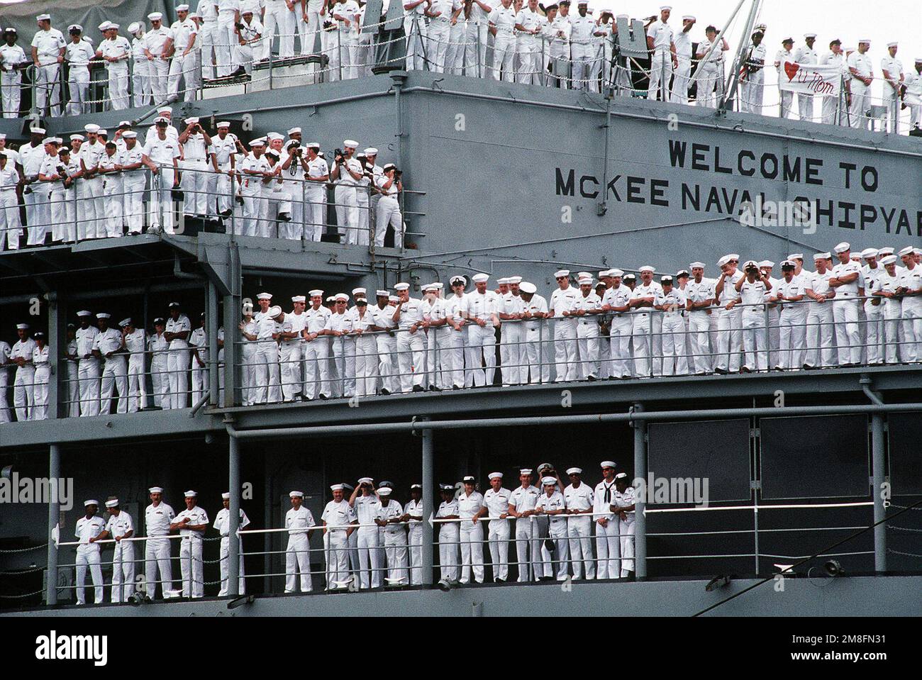 Crew members crowd along the port side of the submarine tender USS ...