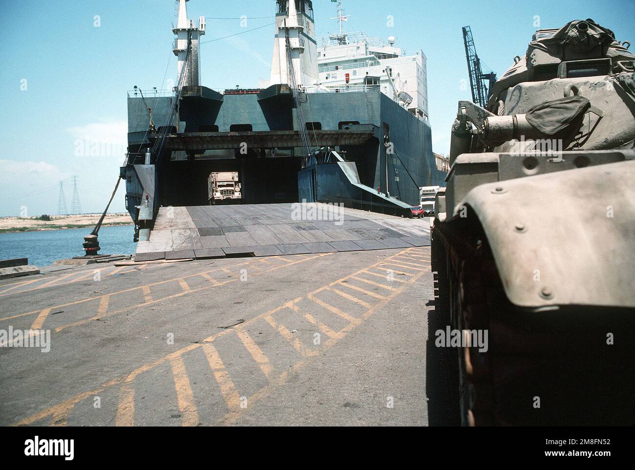 A 5-ton cargo truck carrying a shelter is driven onto the stern ramp of ...