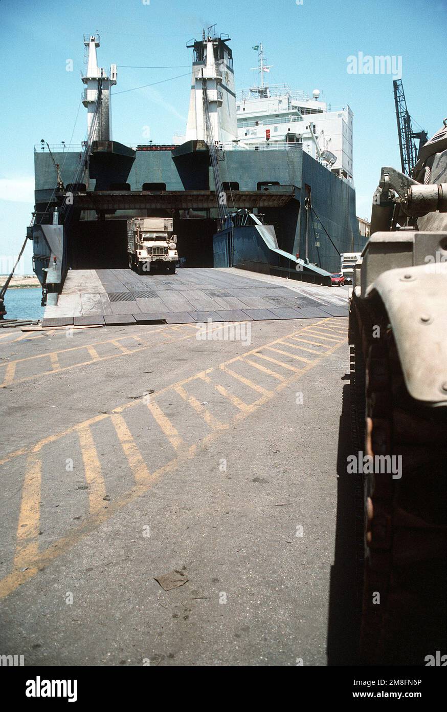A 5-ton cargo truck carrying a shelter is driven onto the stern ramp of ...