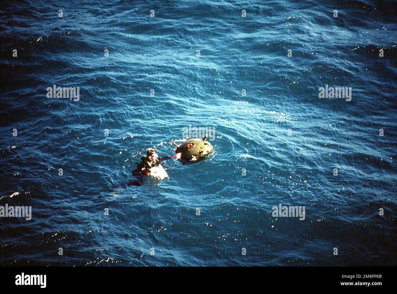An explosive ordnance disposal (EOD) diver attaches plastic explosives ...