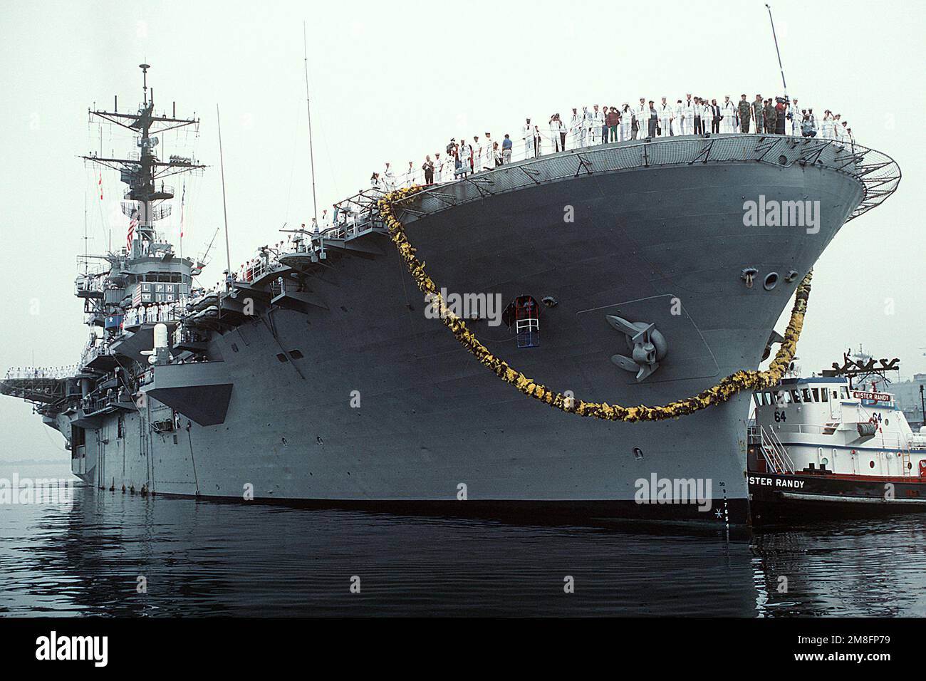 Sailors man the rails and a garland decorates the bow of the amphibious ...