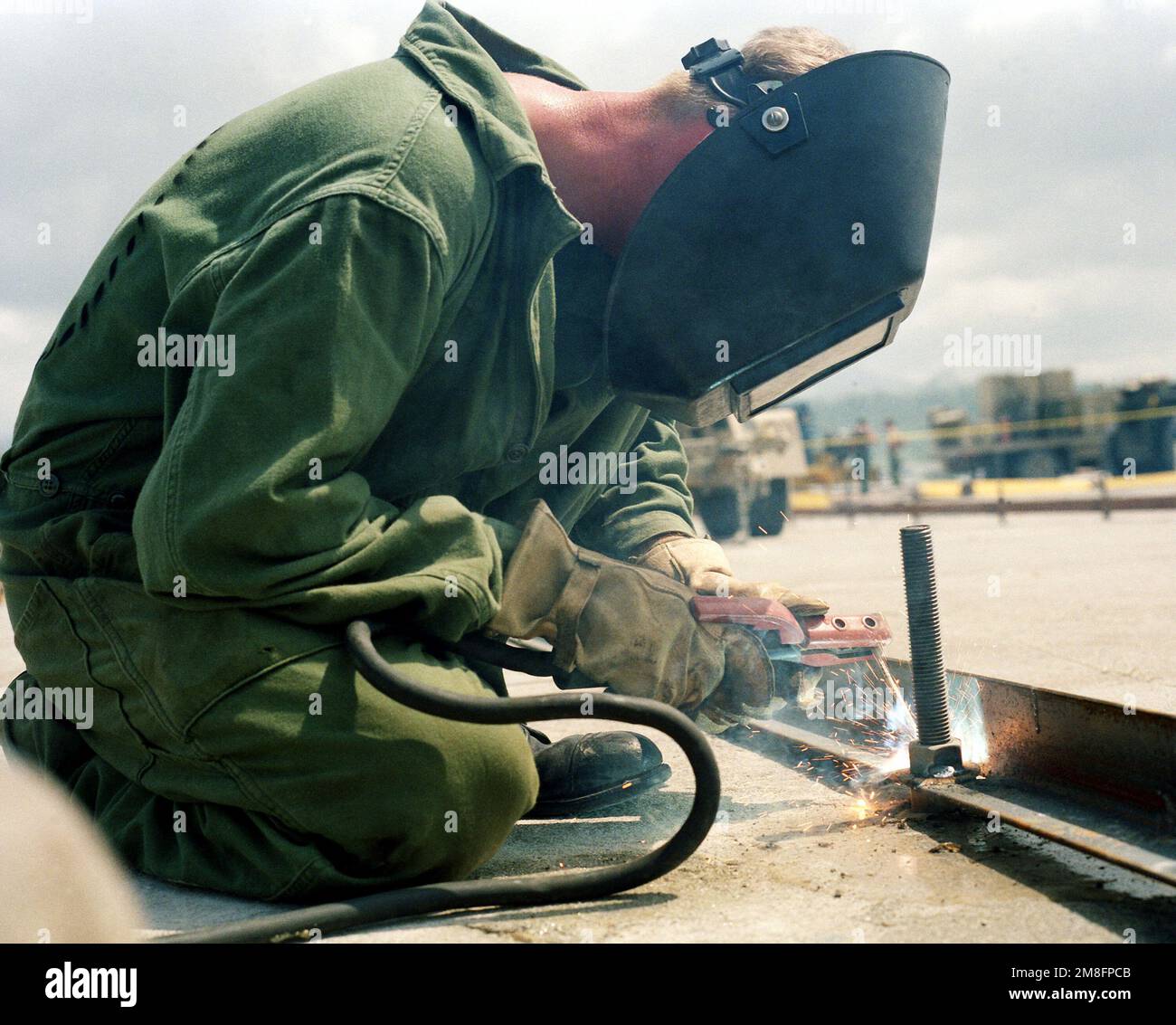 A Seabee uses an arc welder as he assembles the frame for a temporary ...