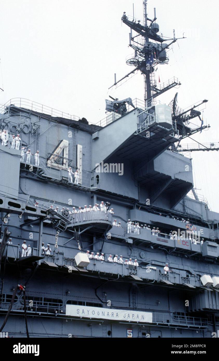 Crew members man the rails on the island of the aircraft carrier USS ...