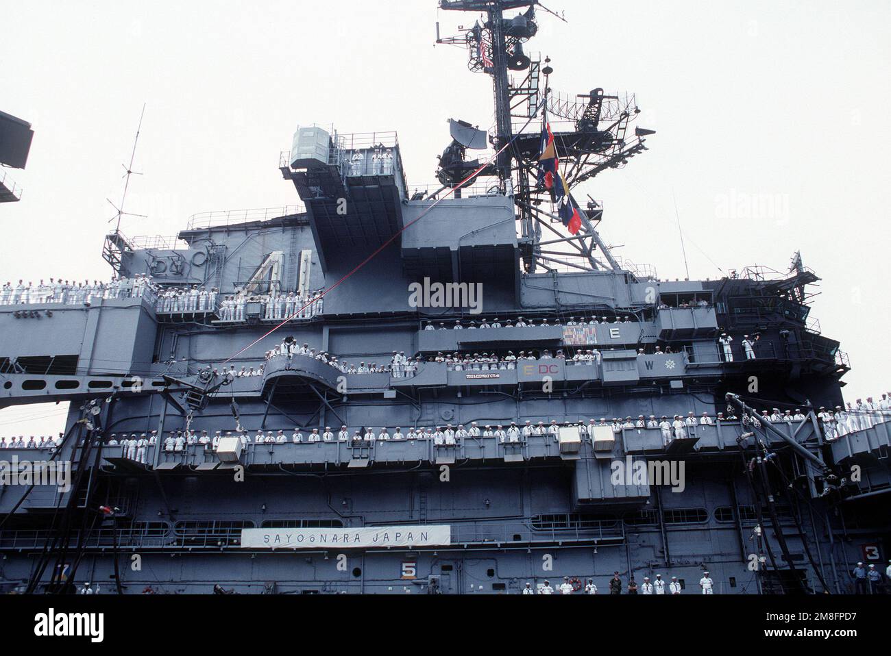 Crew members man the rails on the island of the aircraft carrier USS ...