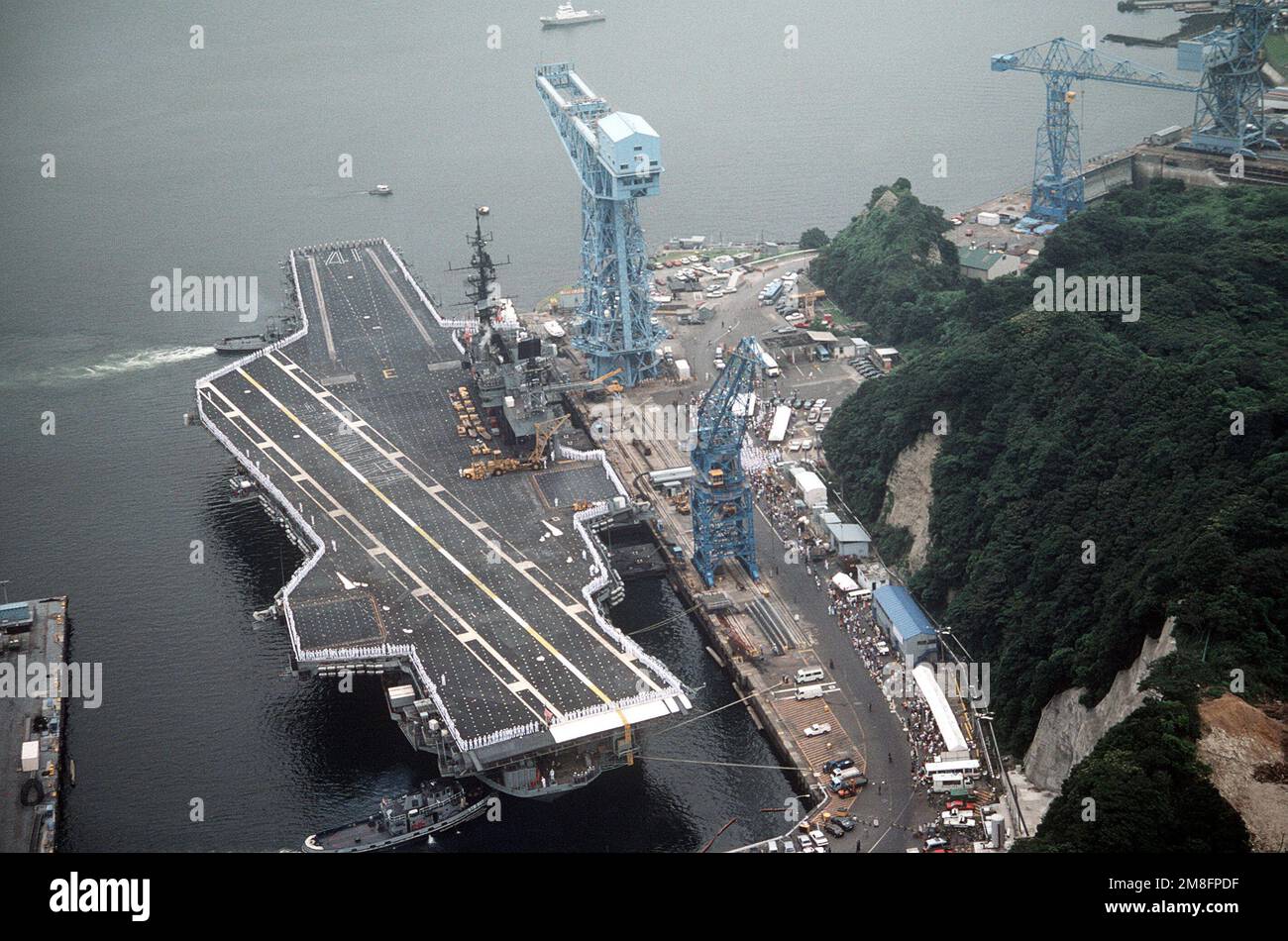 Two large harbor tugs assist the aircraft carrier USS MIDWAY (CV-41) as ...