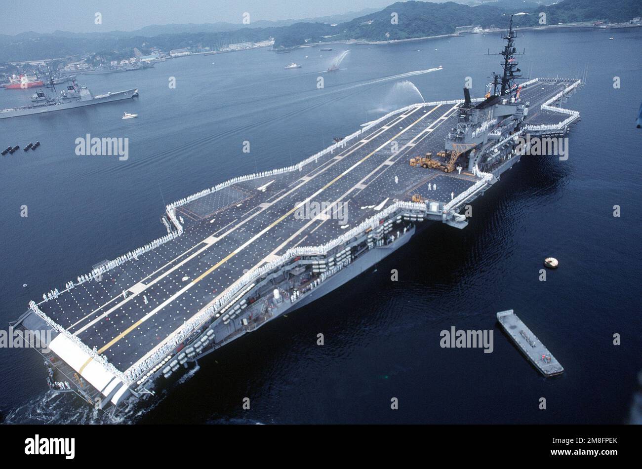 The crew of the aircraft carrier USS MIDWAY (CV-41) mans the rails as ...