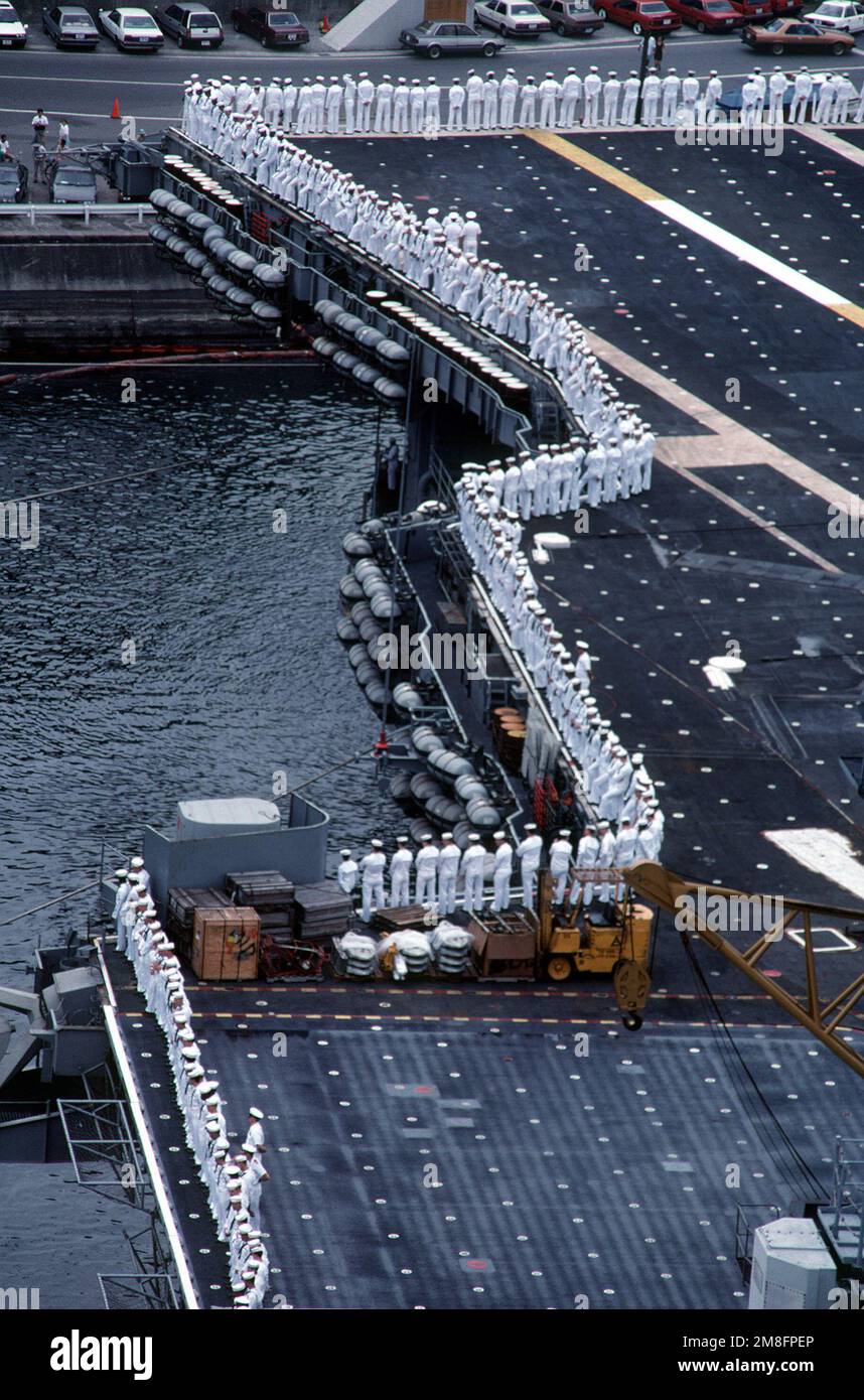 Crew members man the rails on the starboard quarter of the aircraft ...
