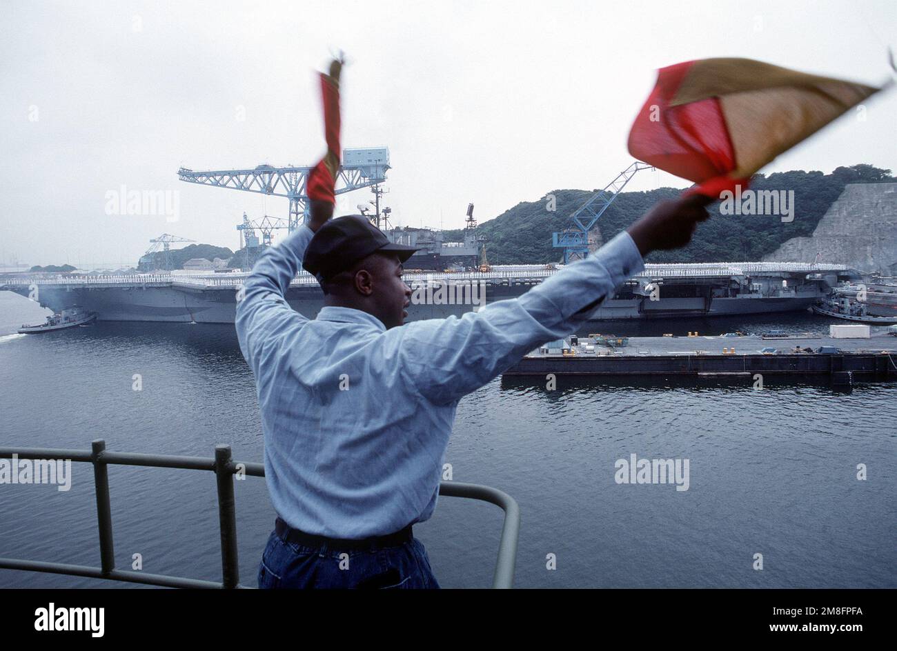 A signalman aboard the amphibious command ship USS BLUE RIDGE (LCC-19) sends a semaphore message ...