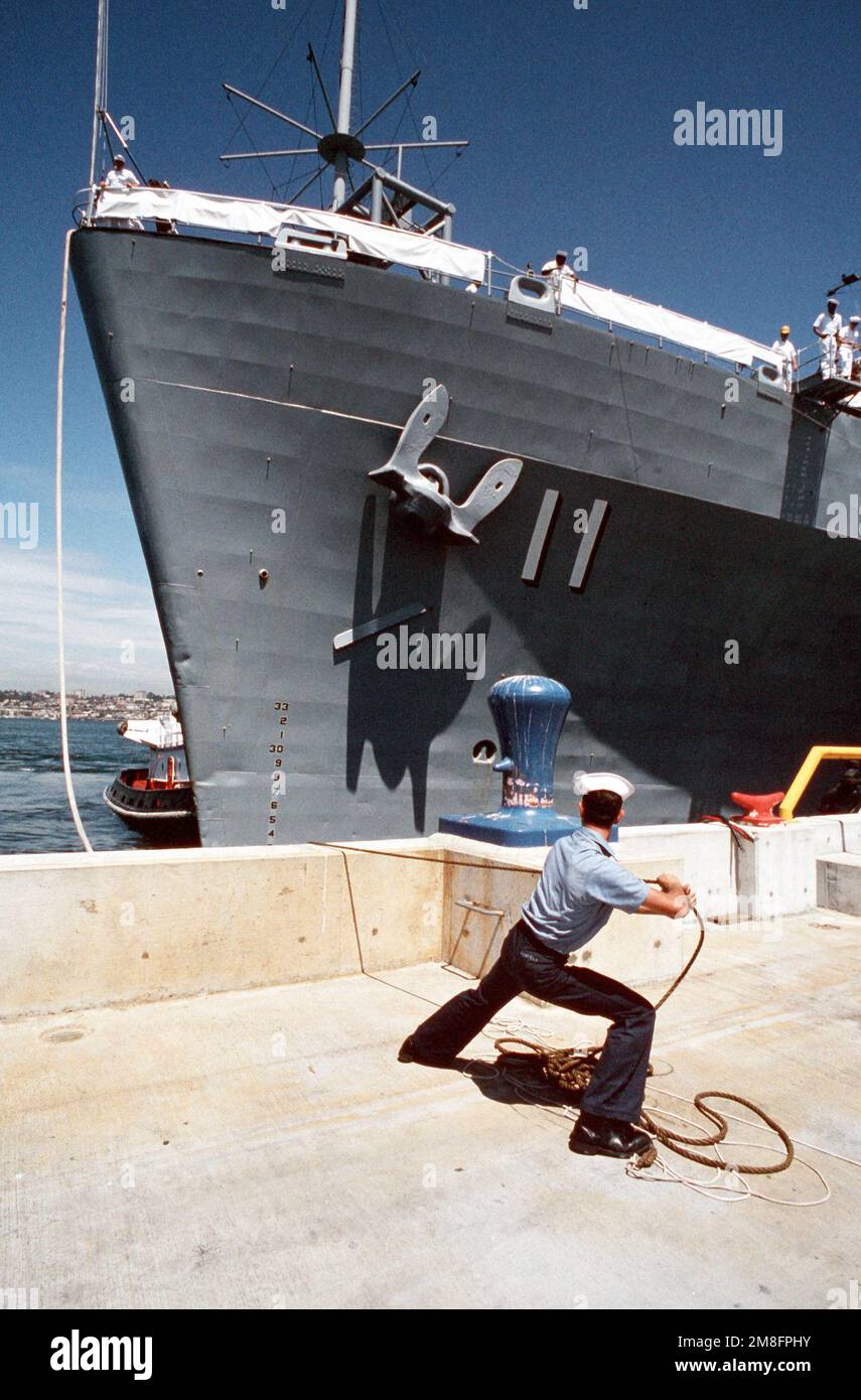 A line handler pulls on a mooring cable as the miscellaneous flagship ...