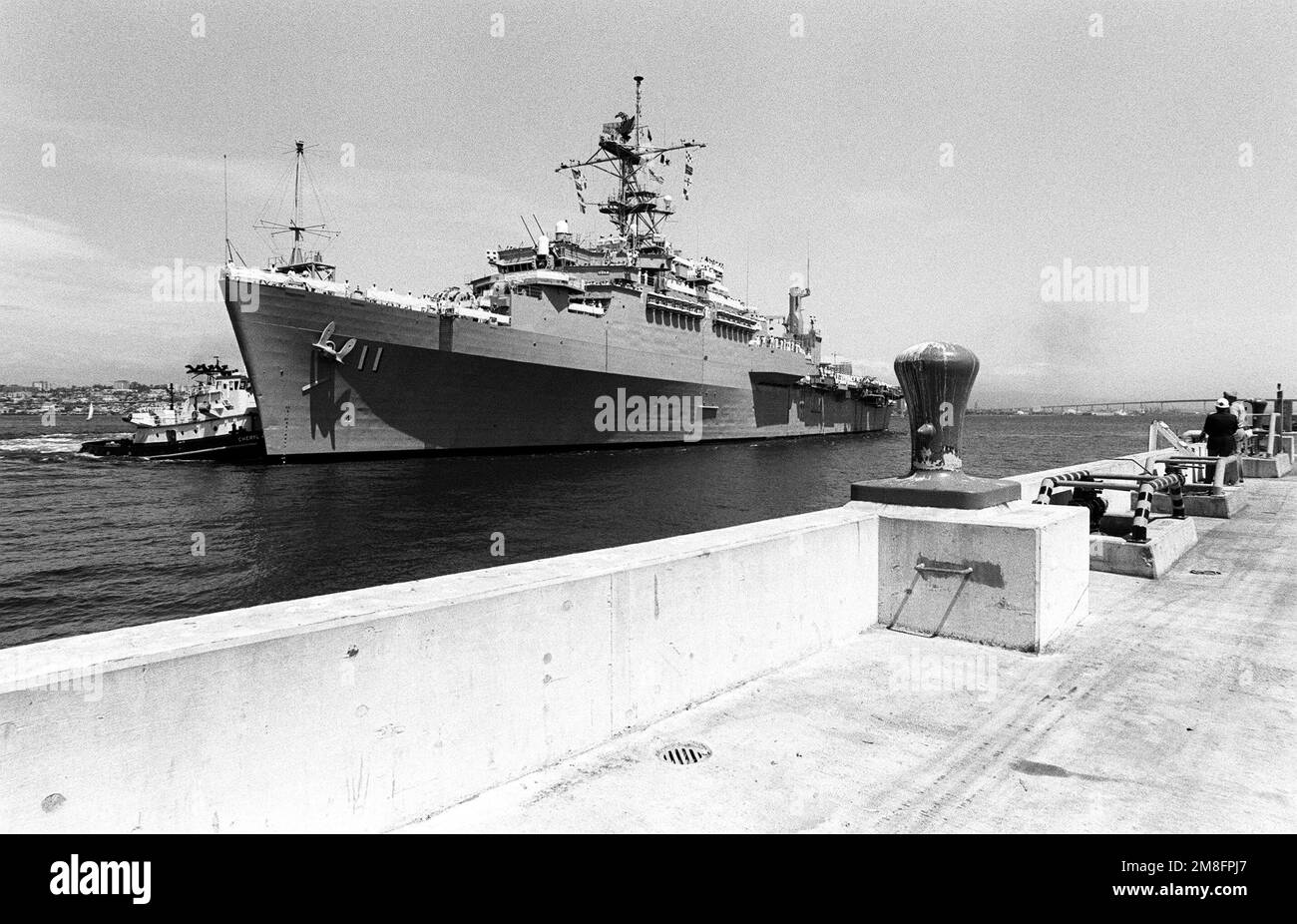 A commercial harbor tug maneuvers the miscellaneous flagship USS ...